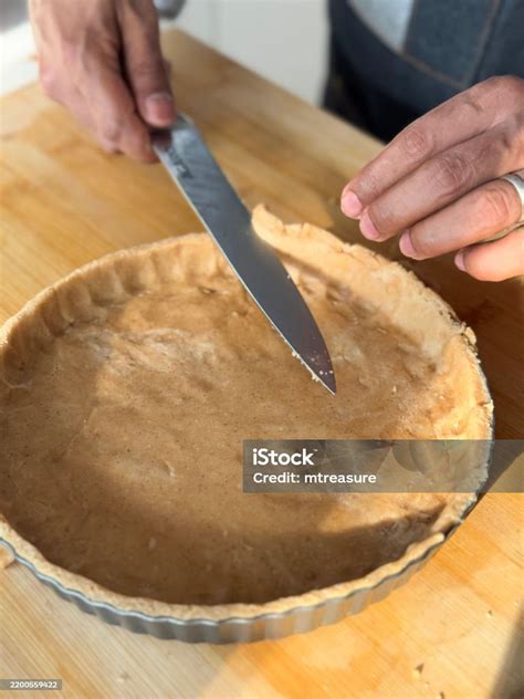 부엌 환경에서 알아볼 수 없는 남자의 풀프레임 이미지 페이스트리 반죽을 깐 타르트 깡통 케이스에서 페이스트리 가장자리 제거 부엌 칼로 파이 크러스트 가장자리 자르기 나무