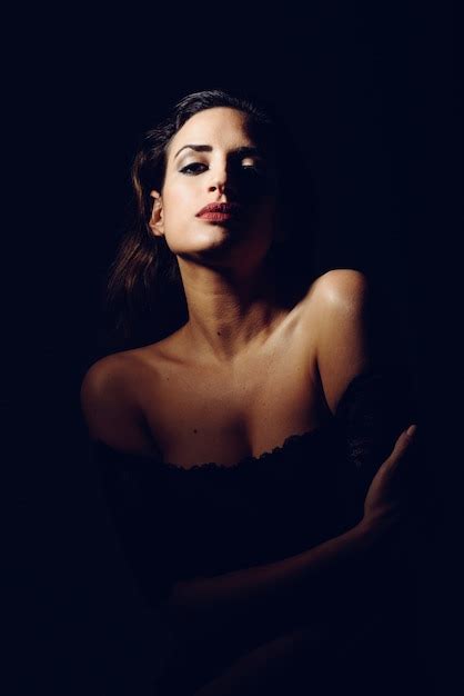 Mulher moreno nova na roupa interior preta na iluminação do claro