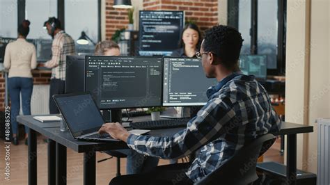 Portrait Of System Engineer Fixing Glasses While Typing On Laptop