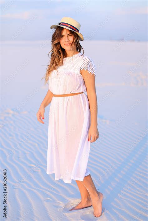 Female Person Wearing White Dress And Hat Standing On Sand In
