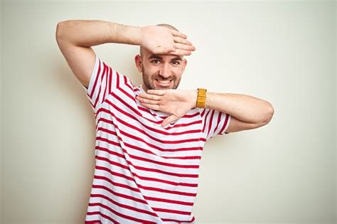 젊은 대머리 남자 수염 캐주얼 스트라이프 빨간 티셔츠 위에 흰색 고립 된 배경 웃고 쾌활 한 재생 얼굴을 보여주는 손으로 우우를