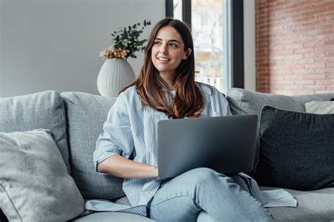 집중된 밀레니엄 세대 소녀는 게으른 주말 동안 집에서 노트북으로 인터넷 검색을 하는 소파에 앉아 컴퓨터 서핑 무선 웹 온라인 쇼핑을 사용하느라 바쁜 젊은 여성 프리랜서 가정