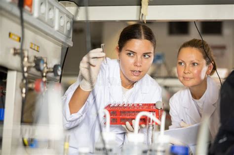 Two Woman Performing Experiments In Laboratory Using Mechanical Lab Pipette For Mixing