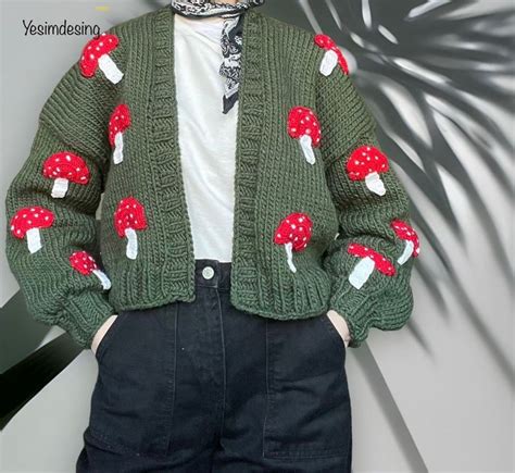A Person Wearing A Green Cardigan With Red Mushrooms On It