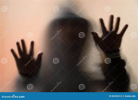 Shadow Blur Of Horror Man In Jacket With Hoodhands On The Glass Stock