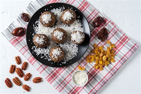 대추 자 두 건포도 땅콩과 코코넛 부스러기로 만든 건강 한 유기농 에너지 볼은 흰색 바탕에 검정색 접시에 있습니다 0명에 대한 스톡 사진 및 기타 이미지 Istock