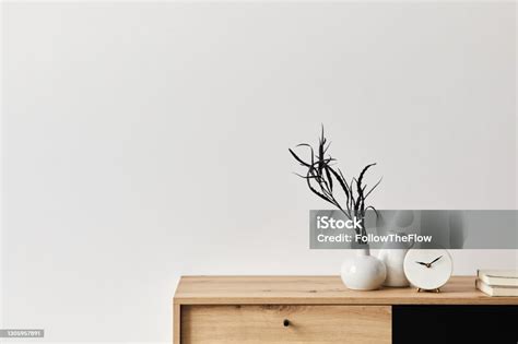 나무 콤모드가 있는 우아한 아파트의 미니멀한 거실 인테리어 세라믹 꽃병잎 시계 현대적인 홈 장식의 우아한 개인 액세서리 공간을 복사합니다 템플릿 장식품에 대한 스톡 사진 및