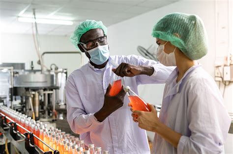 품질 관리 엔지니어는 여성 노동자와 함께 일합니다 공장의 근로자는 고객에게 보내기 전에 병이나 갤런에 대한 메모를 기록합니다 식품 공장의 검사 품질 관리 식품 가공 공장에