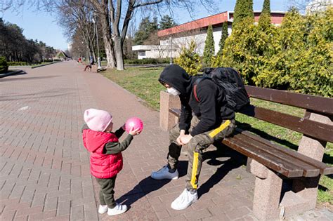 작은 백인 아이는 공공 공원에서 벤치에 앉아 보호 얼굴 마스크에 아픈 백인 남자에 와서 아이는 그에게 코로나 바이러스처럼 보이는