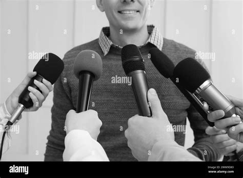 man giving interview to journalists indoors closeup black and white