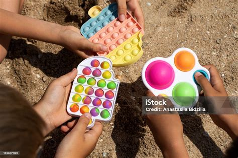 플라스틱과 실리콘에서 트렌디 한 여름 장난감을 가지고 노는 아이들의 그룹 해변에서 팝과 간단한 보조개 어린이와 성인을위한 안티 스트레스 만지작 3 명에 대한 스톡 사진 및