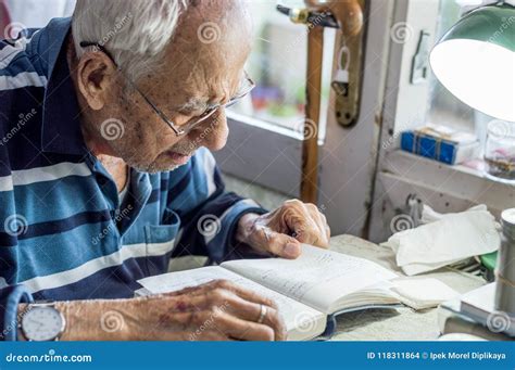Elderly Man With Glasses Reading Writings In Notebook Near The Window