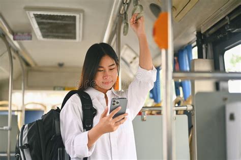 Smiling Female Traveler With Backpack Standing In A Bus And Using Mobile Phone Travel And