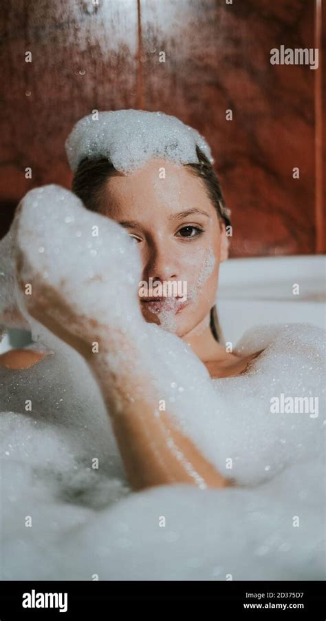 Vertical Shot Of A Beautiful Young Woman Covered In Bubbles While