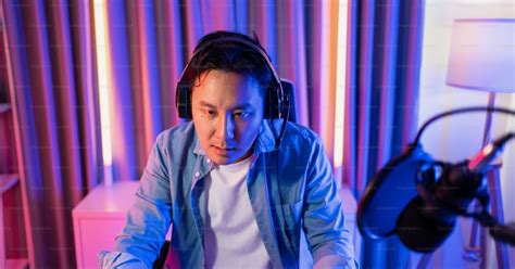 아시아의 매력적인 Esport 남성 게이머는 컴퓨터에서 온라인 비디오 게임을합니다 잘 생긴 남자 게임 플레이어는 행복하고