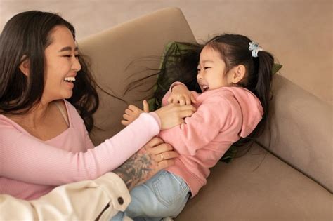 Premium Photo Cheerful Chinese Woman Tickling Little Daughter And