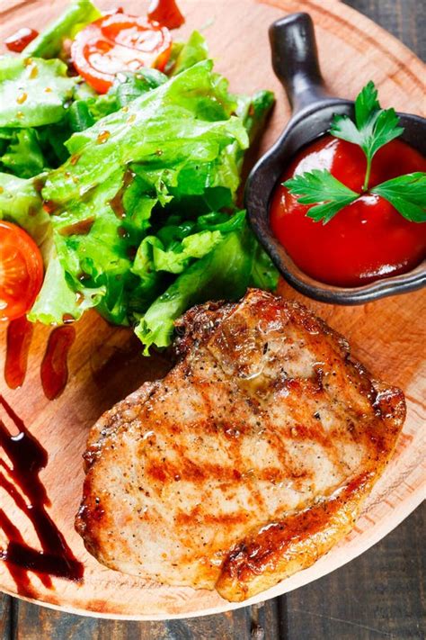 Carne De Porco Grelhada Do Bife Salada Tomates E Molho Do Legume