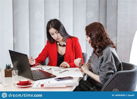 Two Stylish Girls Designers Are Working With Laptop And Documentation At The Project Sitting At