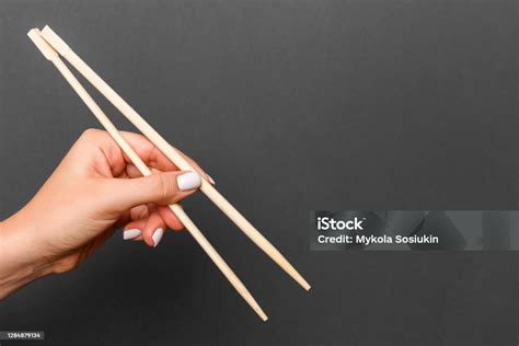 검은 색 배경에 여성의 손에 나무 젓가락의 창조적 인 이미지 복사 공간이 있는 일본식 및 중국 음식 가지 식물 부위에 대한 스톡