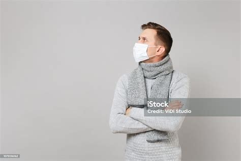 회색 스웨터에서 젊은 남자에 고립 된 회색 배경 접혀 스카프 메 마른 얼굴 마스크 보고 옆으로 손을 잡고 건강 한 생활 습관 병