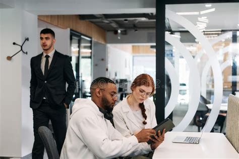 Two Colleagues Collaborating In A Modern Office While Discussing A Project Using A Tablet And