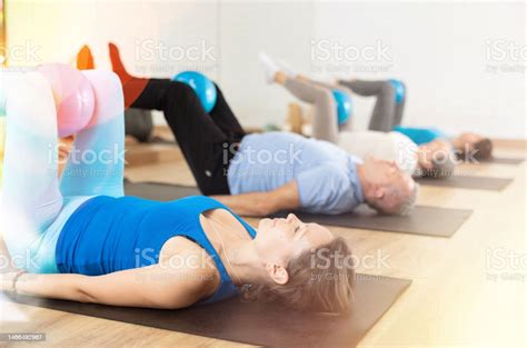 스튜디오에서 필라테스 훈련 중에 다리 사이에 공을 들고 프레스를 누르는 다양한 연령대의 사람들 필라테스에 대한 스톡 사진 및