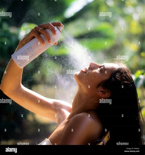 Young Woman Spraying Her Face With Water Atomizer Hi Res Stock