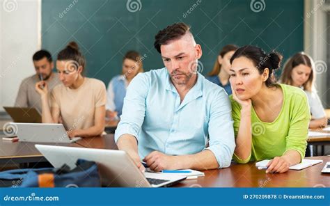 Man And Woman Helping Each Other To Solve Problem On Laptop While Studying In University Class