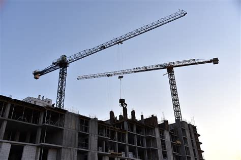 일몰 배경에 건설 현장에서 새로운 주거 건물을 건설 타워 크레인의 실루엣 크레인은 콘크리트 양동이를 들어 올리는 것입니다 양식에 대한 시멘트 믹스를 붓는 빌더 소프트 포커스