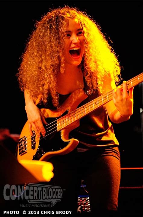 A Woman With Curly Hair Playing A Bass Guitar