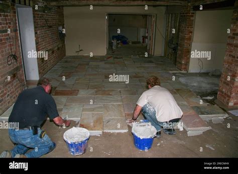 Two Workmen Laying Large Floor Tiles Perhaps Flagstones As Part Of A