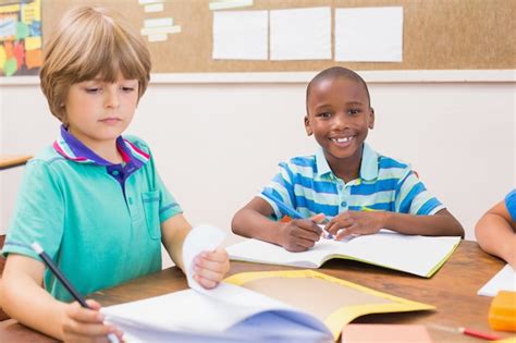Élèves Mignons écrit Au Bureau Dans La Salle De Classe Photo Premium