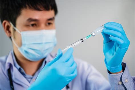 Premium Photo Male Doctor Drawing Vaccine Bottle Into Syringe
