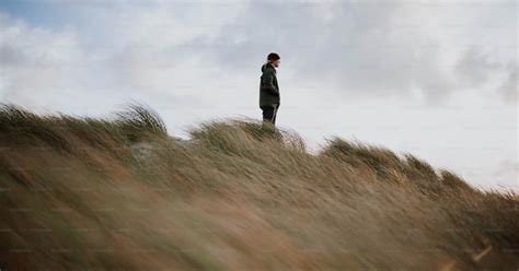 풀로 덮인 언덕 위에 서 있는 남자 사진 Unsplash의 부담 이미지