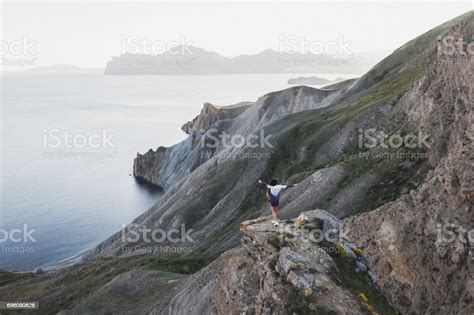 언덕 및 산의 배경으로 바다의 멋진 볼 수 있는 절벽에 서 있는 여자 그녀는 행복 하 고 즐기는 자유의 순간 Koktebel에