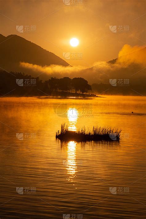 早晨的太阳倒映在湖面和橙色的天空上