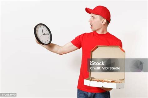 흰색 배경에 고립 된 빨간 유니폼에 배달 남자 남성 모자 티셔츠 골 판지 Flatbox 및 시계 이탈리아 피자를 들고 택배로 일하고 있는 시간에 보여주는 광고에 대 한