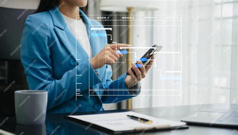 프로젝트 매니저는 이정표와 진행 계획과 Gantt 차트 스케줄링 다이어그램으로 작업하고 업무에서 스마트 폰 태블릿과 노트북으로 작업합니다 프리미엄 사진