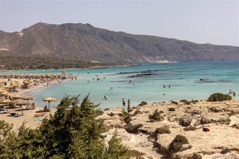 People Relaxing On The Famous Pink Coral Beach Of Elafonisi On Crete