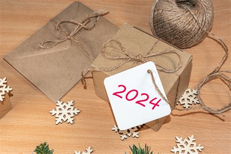 2024년 새해 복 많이 받으세요 나무 눈송이가 있는 테이블에 2024라는 라벨이 붙은 공예 종이로 만든 선물 12월에 대한