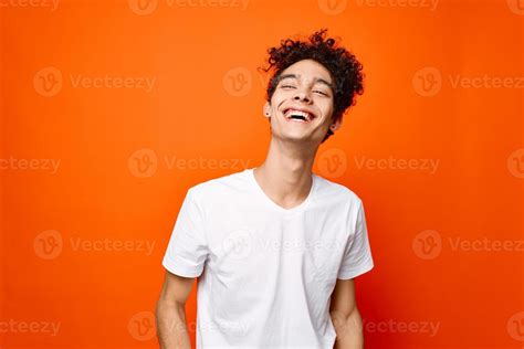 Guy In A White T Shirt Gesturing With His Hand On An Orange Background