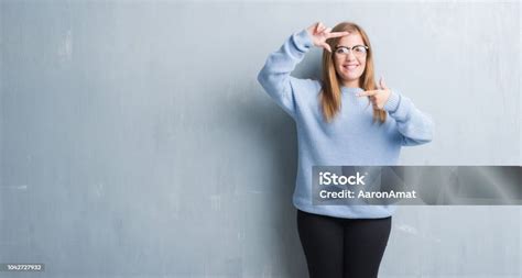 웃 고 행복 한 얼굴로 손가락과 손으로 만드는 프레임 안경을 쓰고 회색 그런 지 벽에 젊은 성인 여자 창의력과 사진 개념입니다