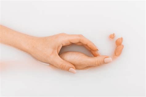 매니큐어 클로즈업으로 아름다운 여자의 손톱 우유 욕조에서 여성 손의 상위 뷰입니다 아름 다운 여성 손입니다 손 관리 손 피부를