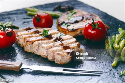 구운된 돼지고기 볶음 야채 토마토 콩 블랙 슬레이트에 소스와 스테이크 거품과 신선한 고기입니다 어두운 배경입니다 구이 및 바베 큐 개념 가금류에 대한 스톡 사진 및 기타