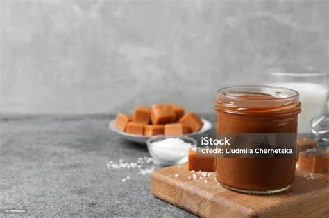 유리 항아리에 맛있는 소금에 절인 캐러멜과 회색 테이블에 사탕 텍스트를위한 공간 0명에 대한 스톡 사진 및 기타 이미지 0명