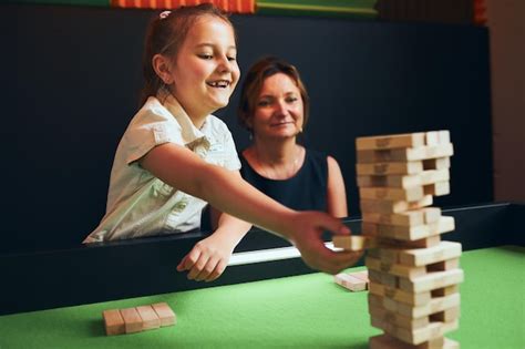 Premium Photo Excited Girl Playing Jenga Game With Her Mom In Play