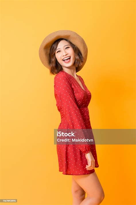 빨간 드레스와 밀짚 모자를 입고 오렌지 색 배경을 가진 행복한 활기찬 아시아 여성의 스튜디오 샷 행복에 대한 스톡 사진 및 기타