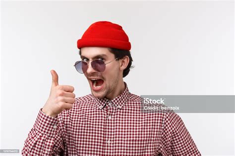 콧수염을 가진 흥분 잘 생긴 재미 젊은 남자 선글라스와 빨간 힙스터 비니를 착용 엄지 손가락을 보여주는 카메라를 보고 구매 제품을 장려 만족 칭찬 친구 작업 긍정적인 감정