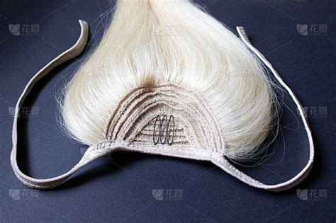 金发自然的头发延伸近距离在一个黑色的背景。马尾辫用深色的头发和浅色的领带做成的马尾辫。