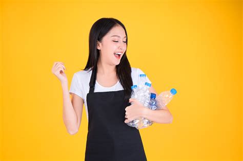 매력적인 아시아 여성 미소는 재활용을위한 쓰레기 봉투에있는 플라스틱 병에 손가락을 가리키는 앞치마를 착용 세계 환경의 날